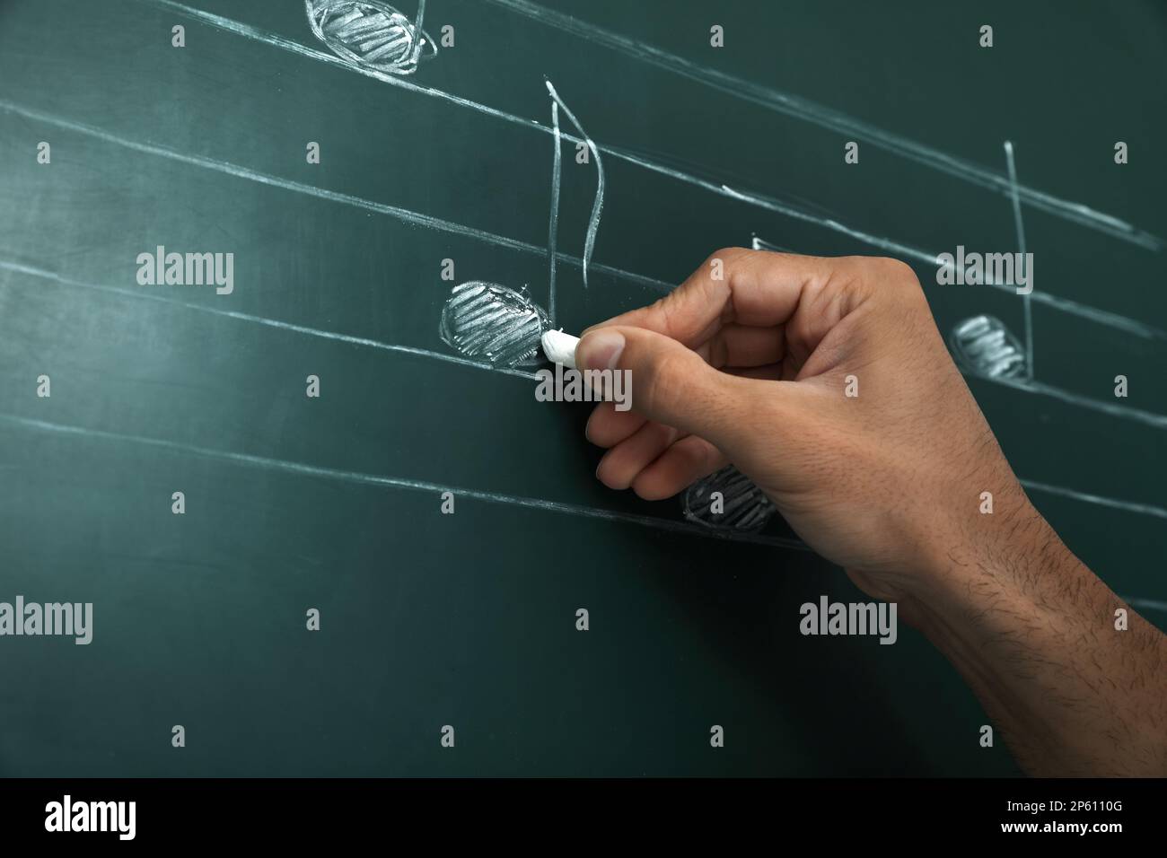 Teacher writing music notes with chalk on greenboard, closeup Stock ...