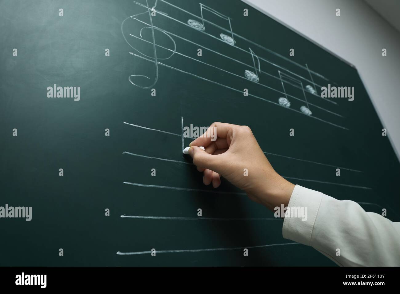 Teacher writing music notes with chalk on greenboard, closeup Stock ...