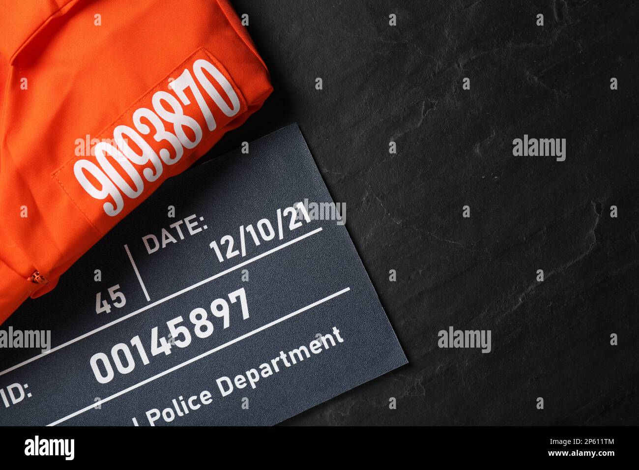 Mugshot letter board and prison uniform on black table, flat lay. Space ...