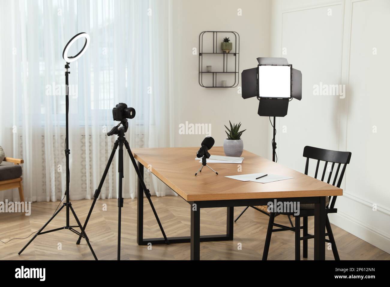 Camera and lighting equipment on tripods near table in room. Blogger ...