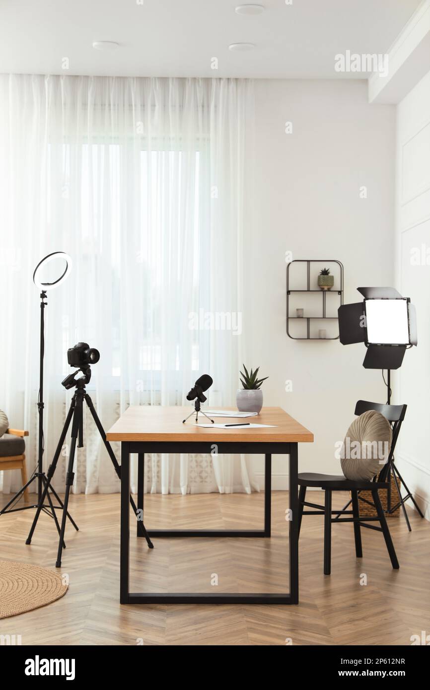 Camera and lighting equipment on tripods near table in room. Blogger ...