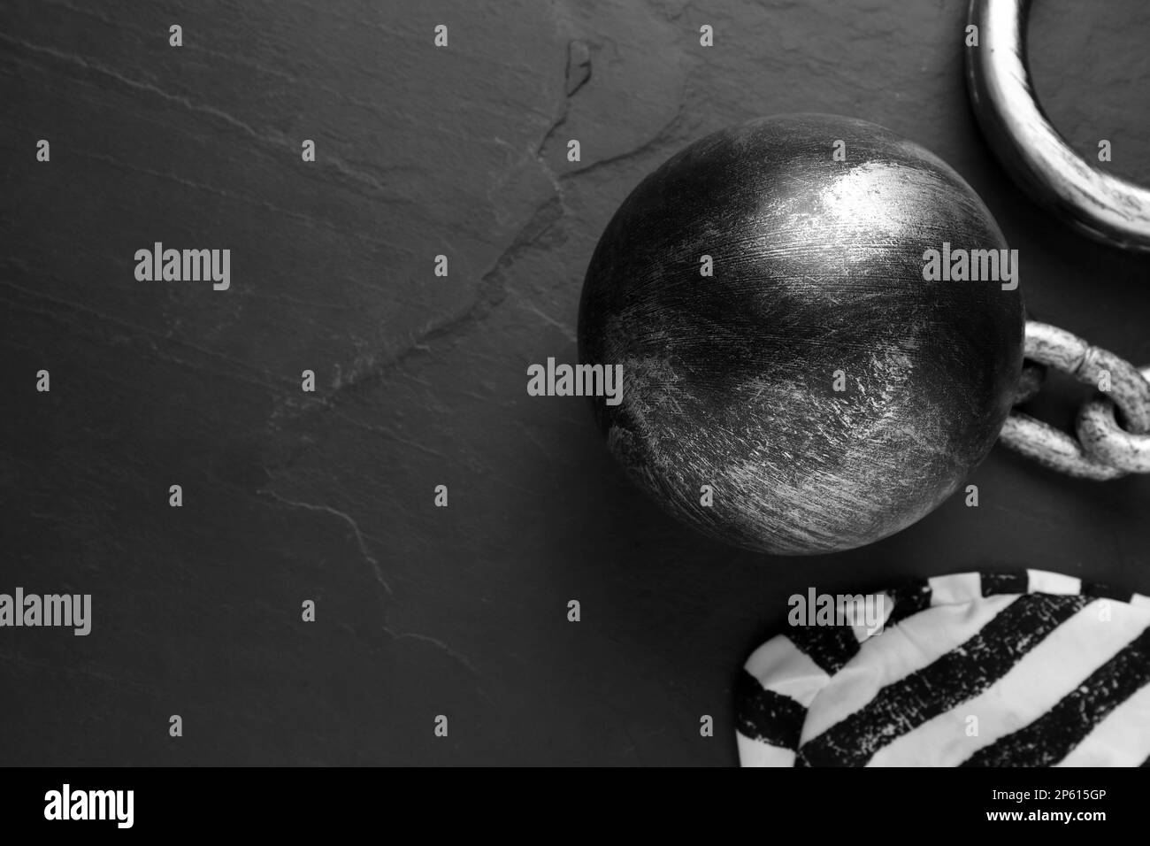 Prisoner ball with chain and jail cap on black table, flat lay. Space ...