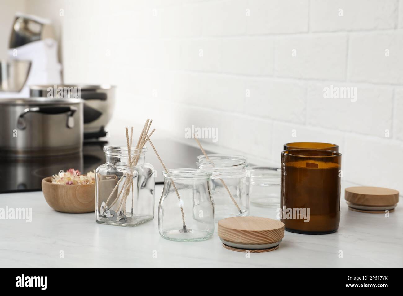 Glass jars with wicks and dry flowers near homemade candles on kitchen ...