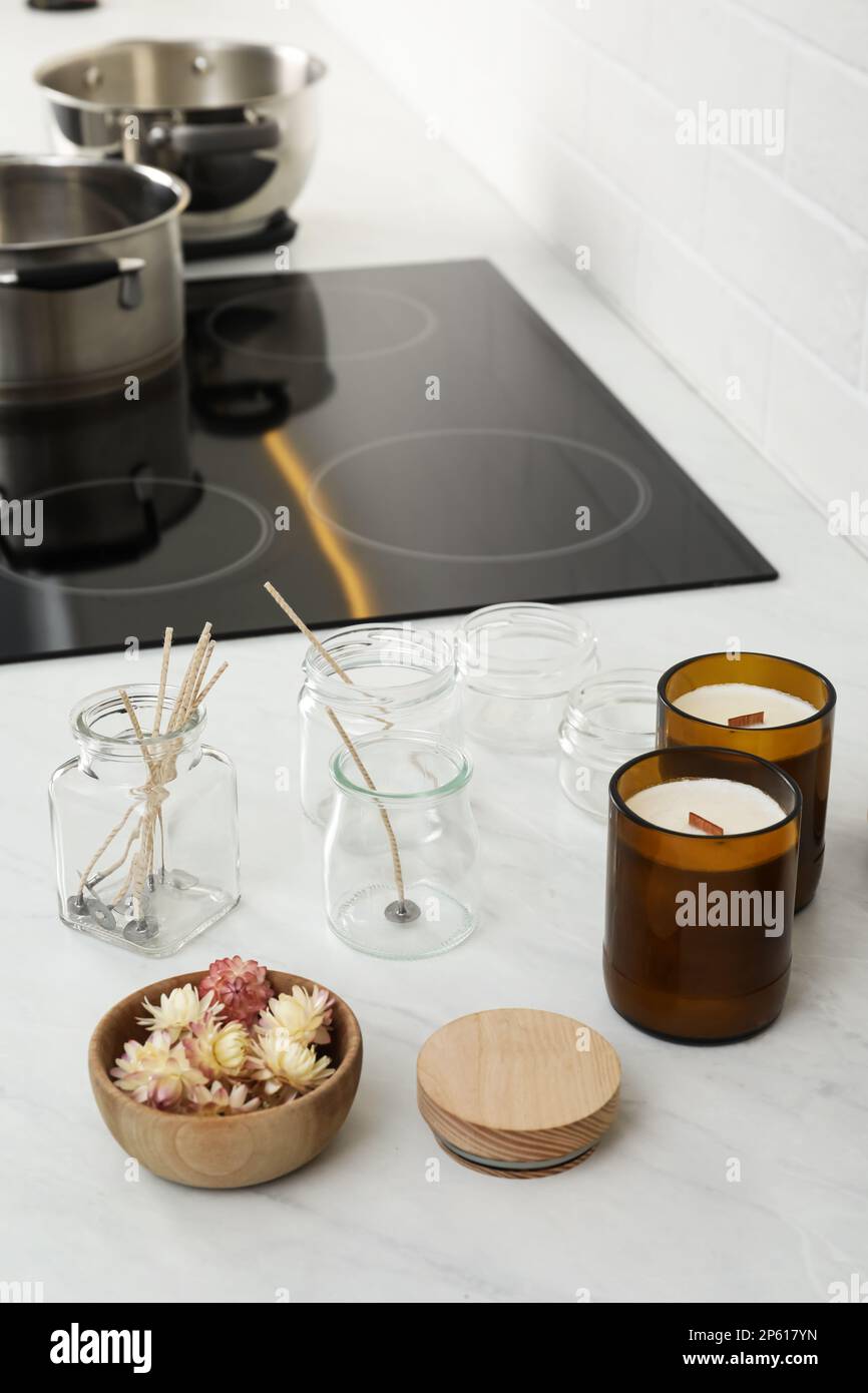 Glass jars with wicks and dry flowers near homemade candles on kitchen ...