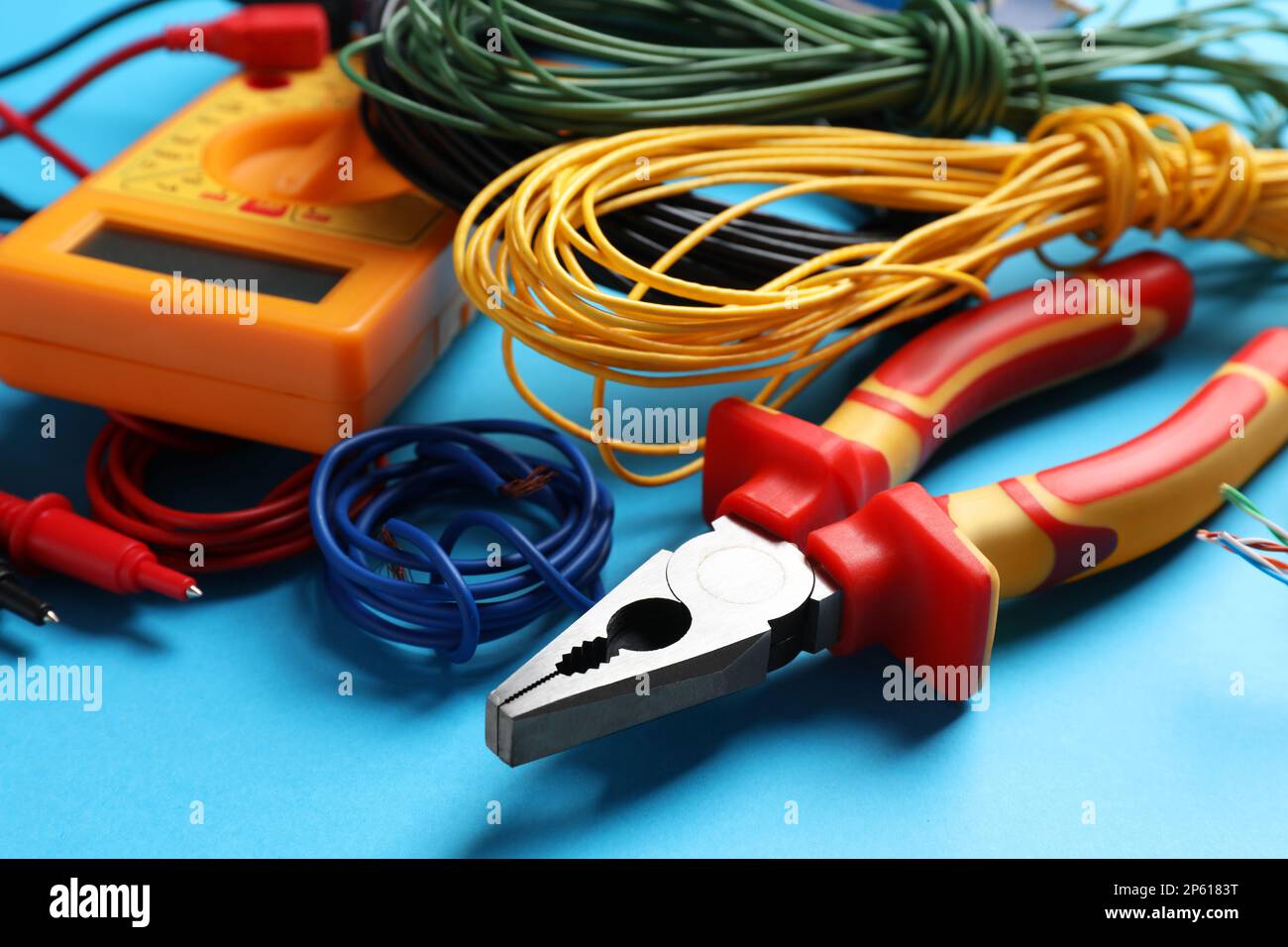 Set of electrician's tools and accessories on light blue background ...