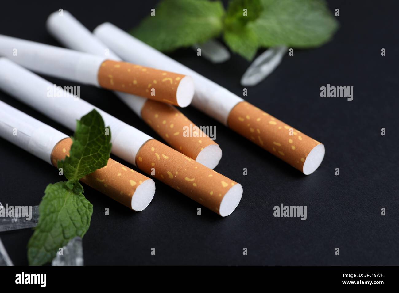 Cigarettes, menthol crystals and mint on black background, closeup ...
