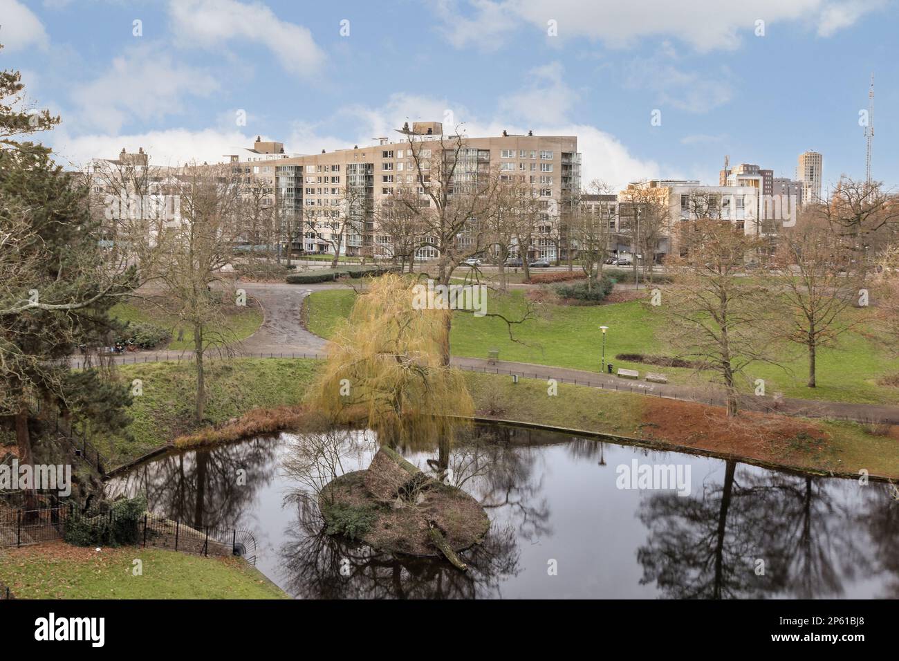 a pond in the middle of a city with buildings on both sides and trees ...