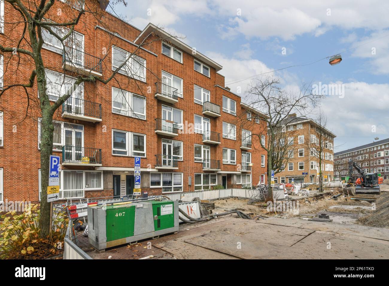 a building under construction in an urban area with trees and trash ...