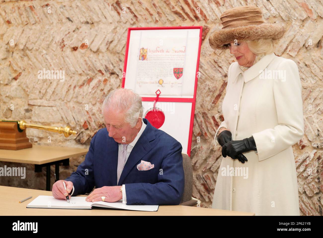 King Charles III and the Queen Consort sign a visitors' book during a ...
