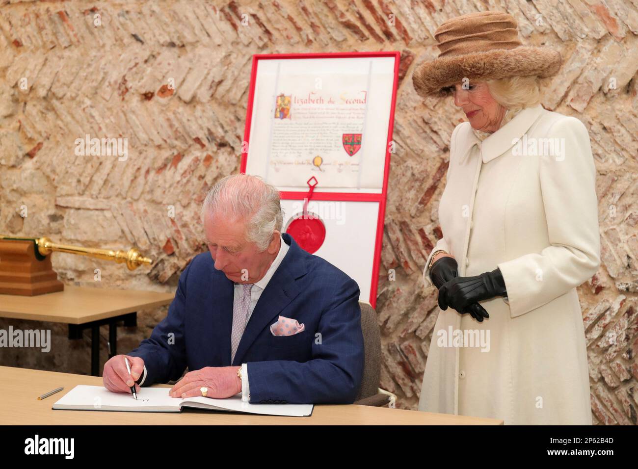 Britain's King Charles signs a visitors' book next to Britain's Camilla ...