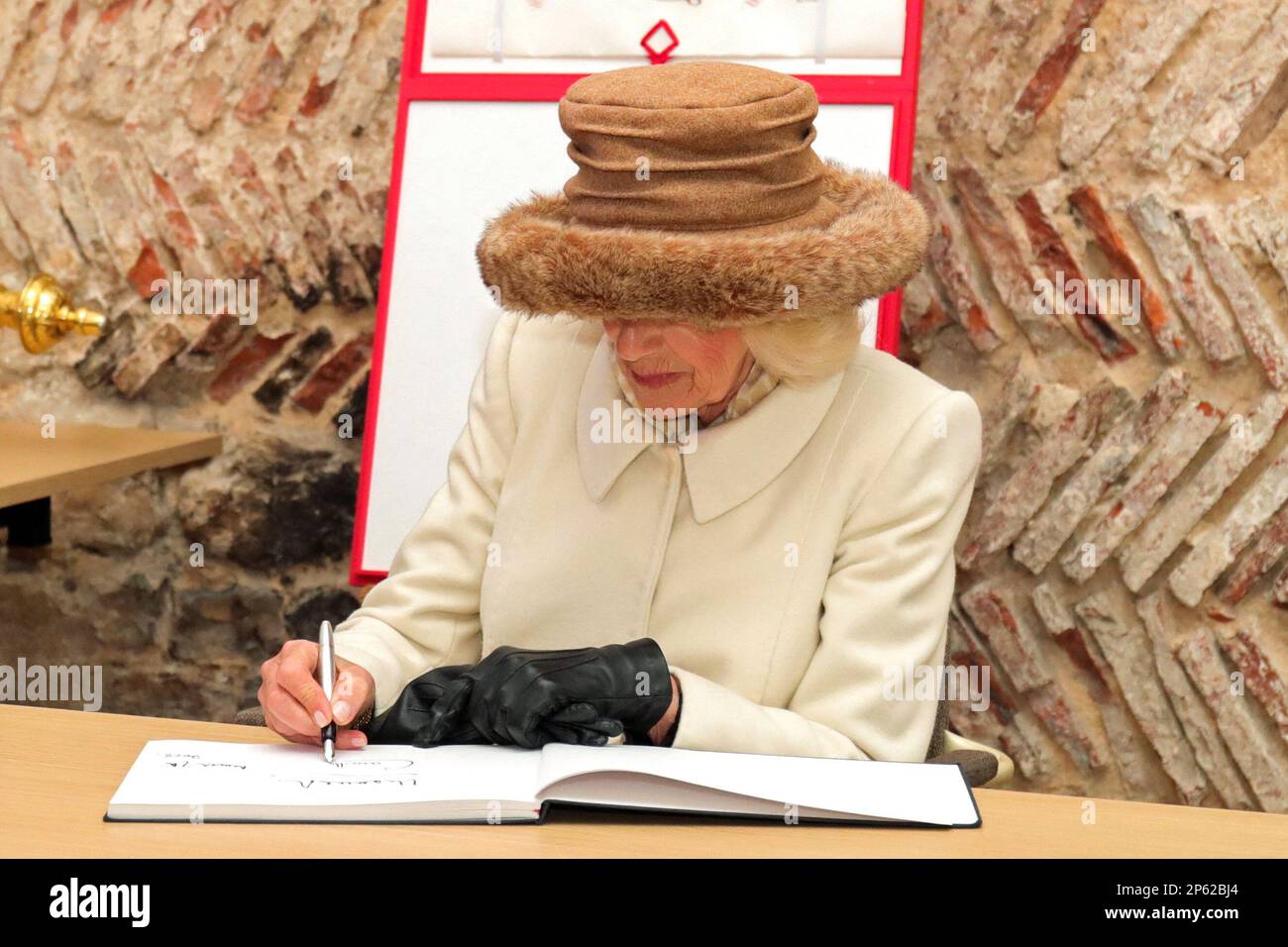 The Queen Consort signs a visitors' book during a visit to Colchester ...