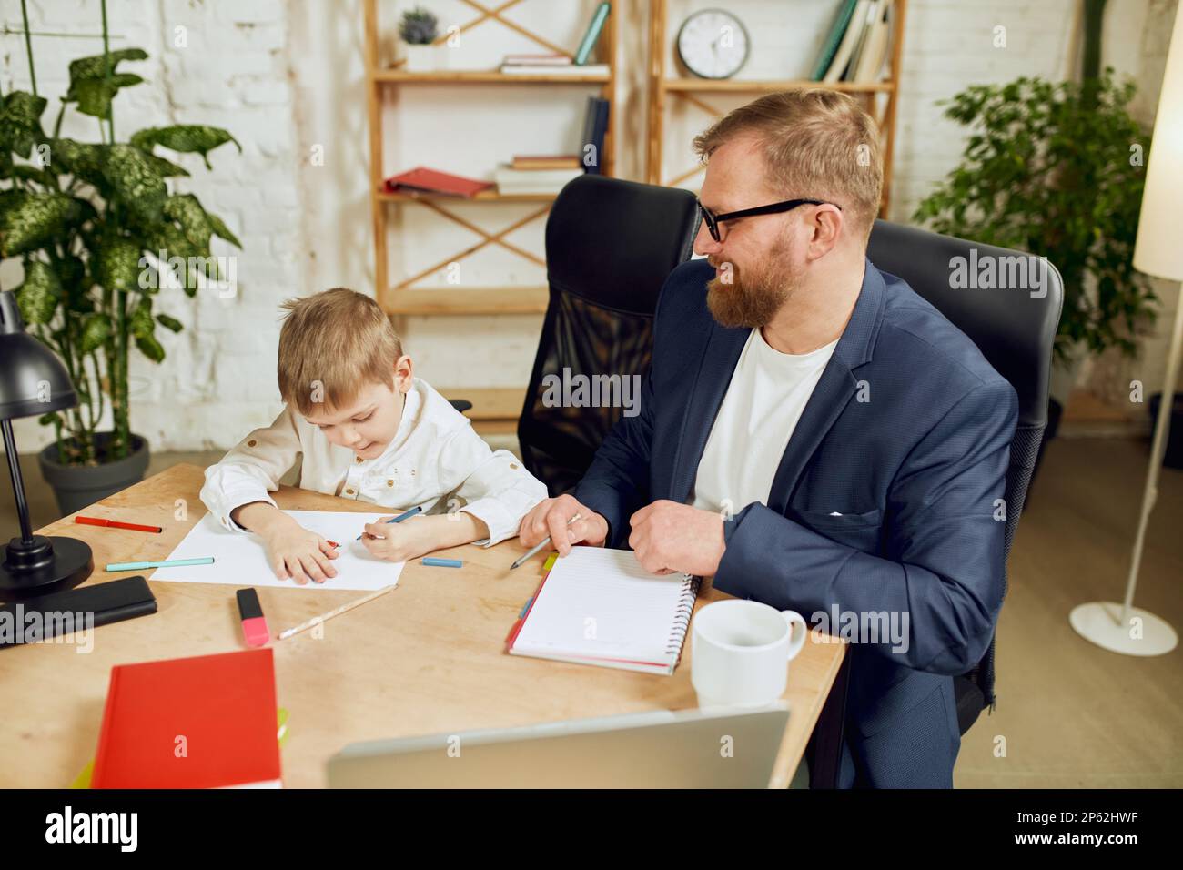 Mature man, father sitting at table, working remotely at home and doing ...