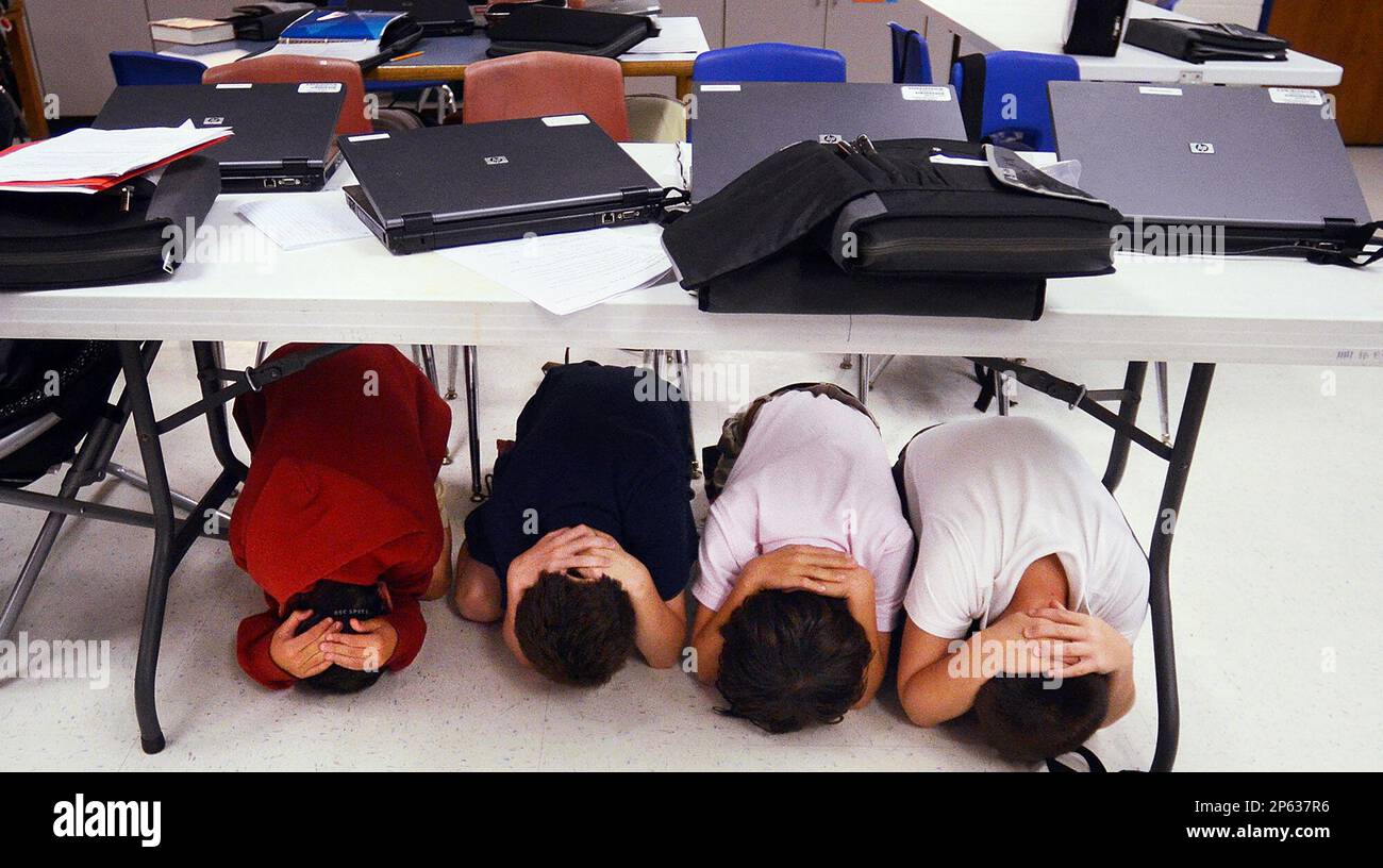 Fifth-graders take cover under a table during an earthquake drill at ...