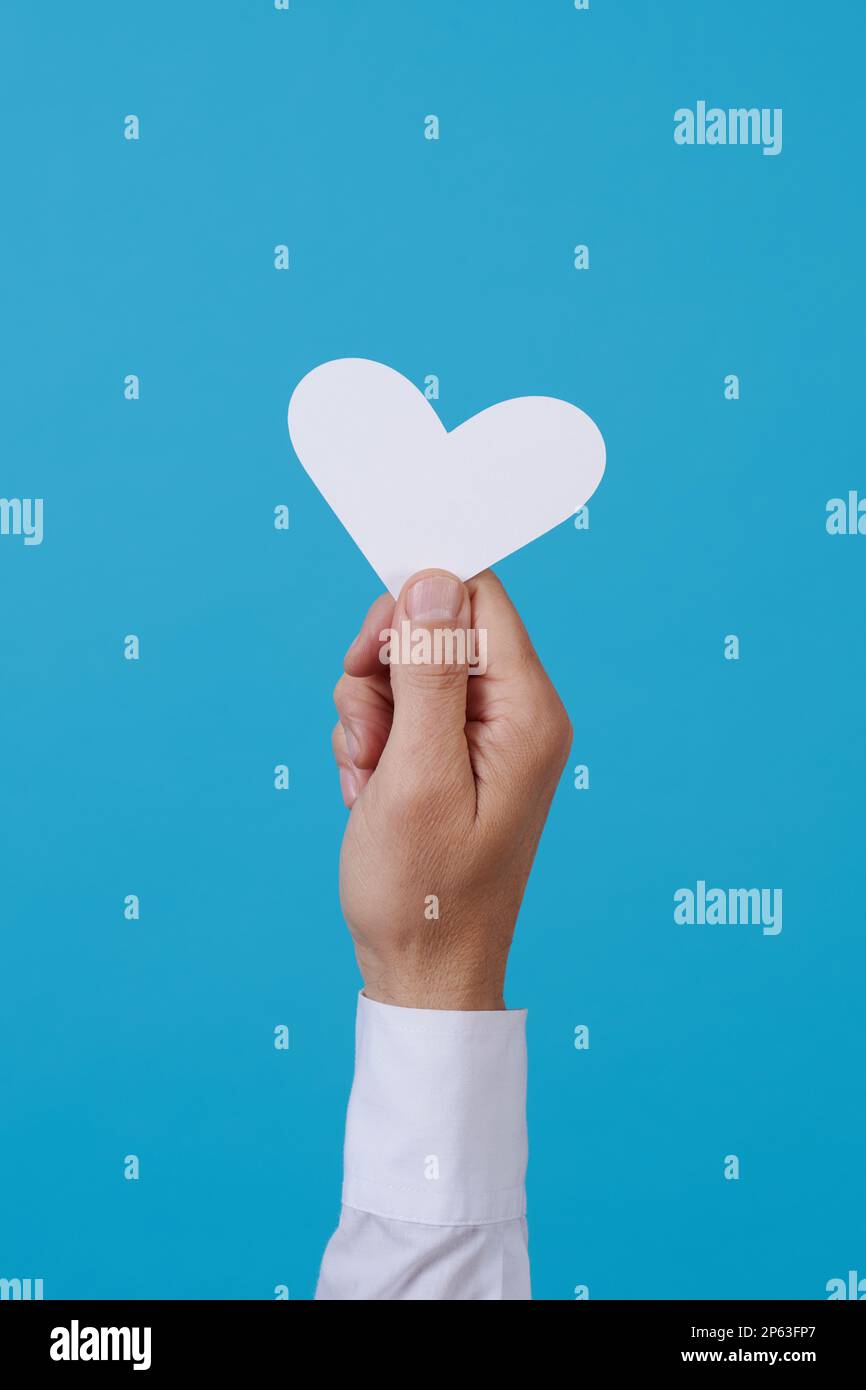 man holding a white heart in his hand against a blue background with ...