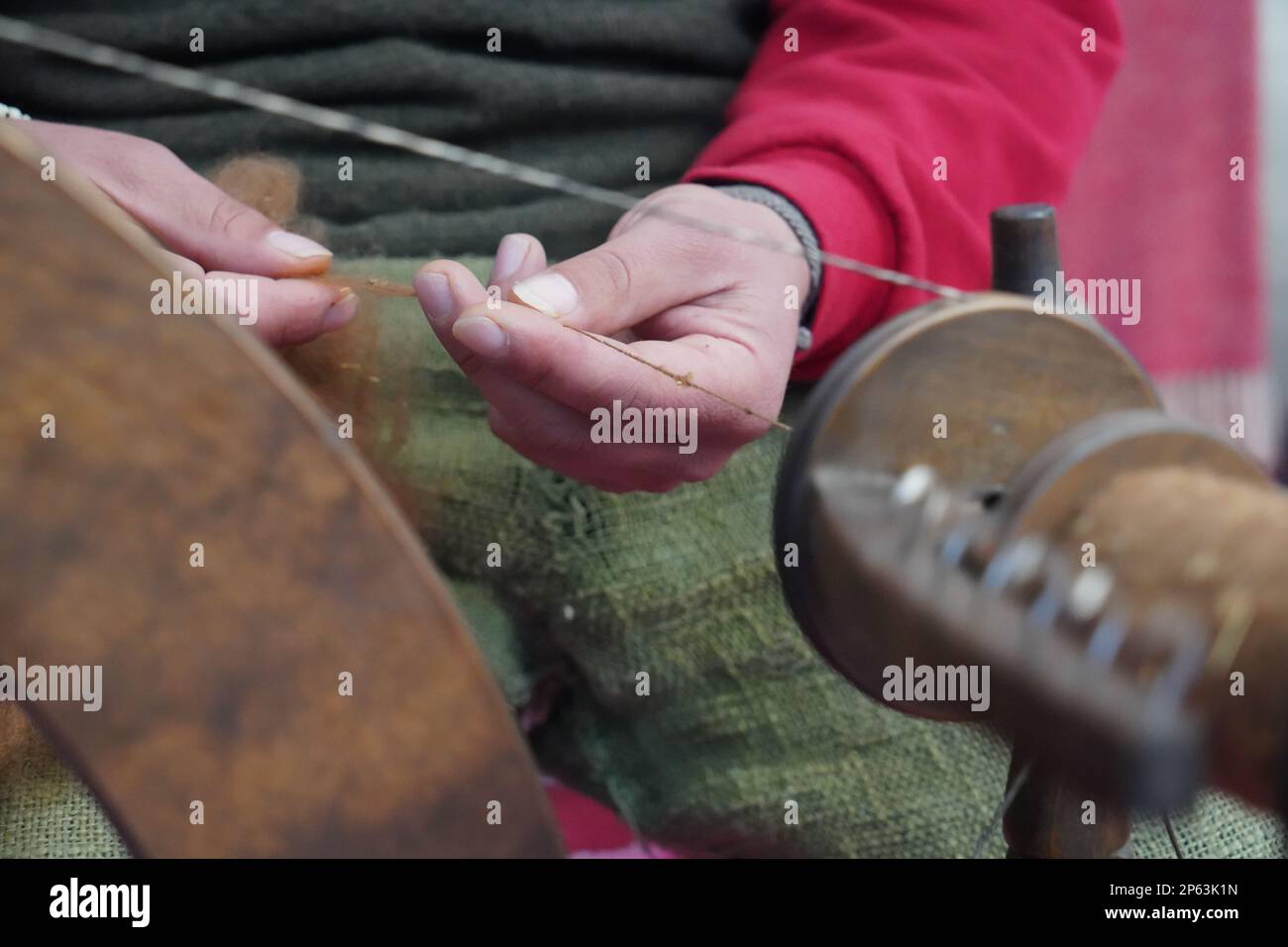 A street artist sewing manufacturing with traditional spinning wheel ...