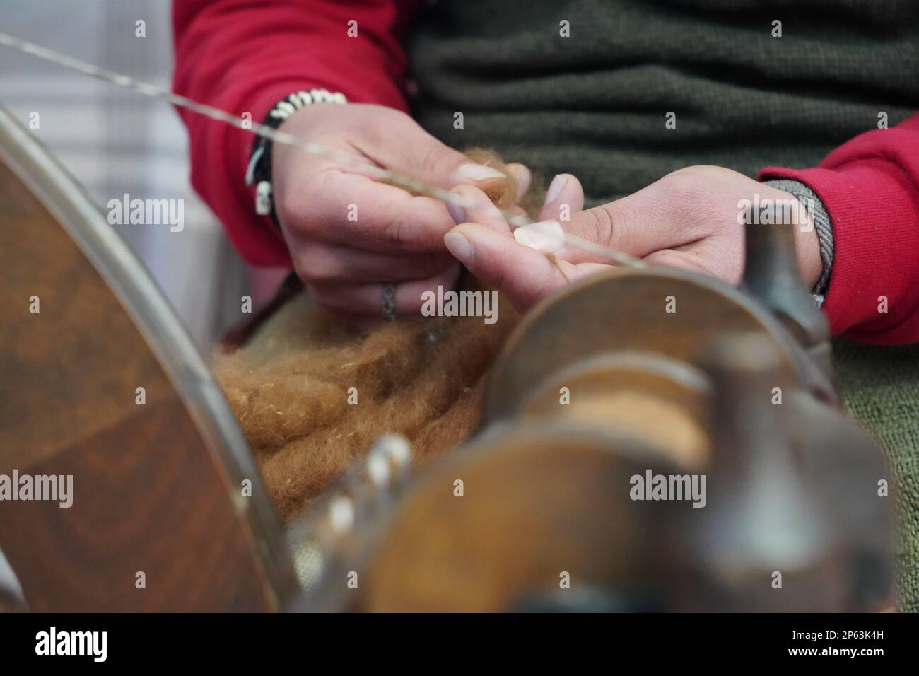 A street artist sewing manufacturing with traditional spinning wheel ...