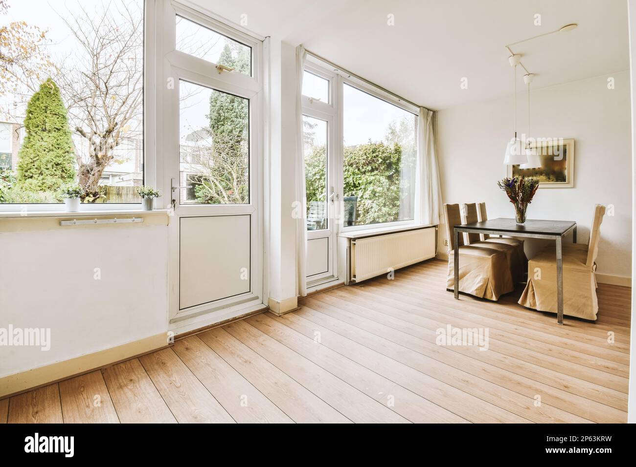 a living room with wood flooring and large windows that look out onto ...