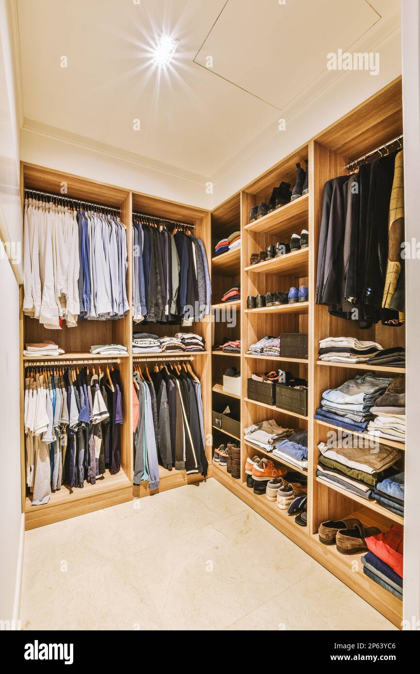 the inside of a walk - in closet with clothes and shoes hanging on ...