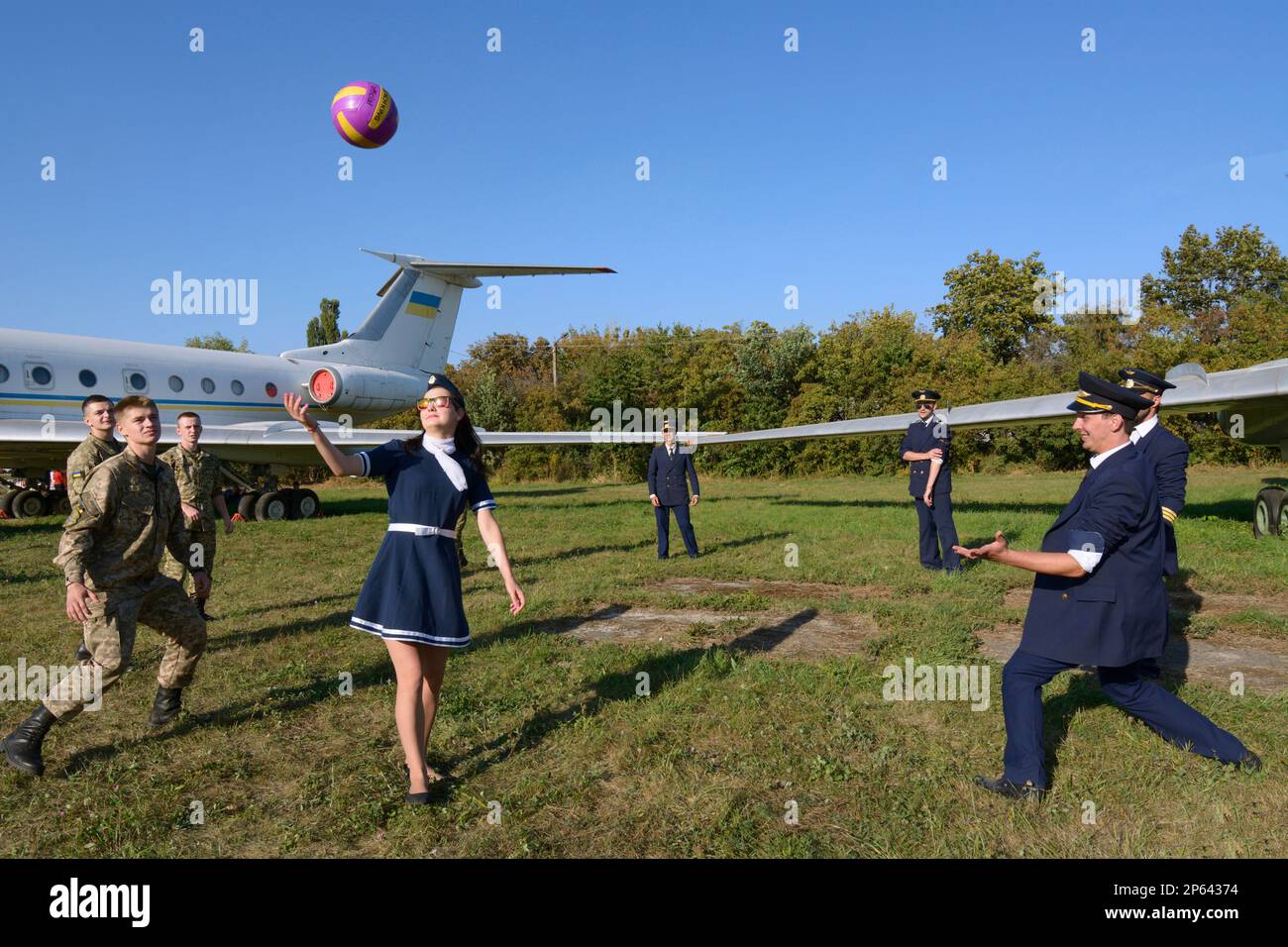 Young people soldiers, pilots and stewardesses playing volleyball ...