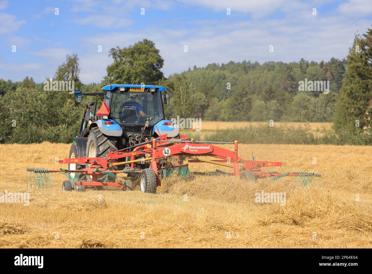 Farmer working in field with tractor and Kverneland Taarup twin rotary ...
