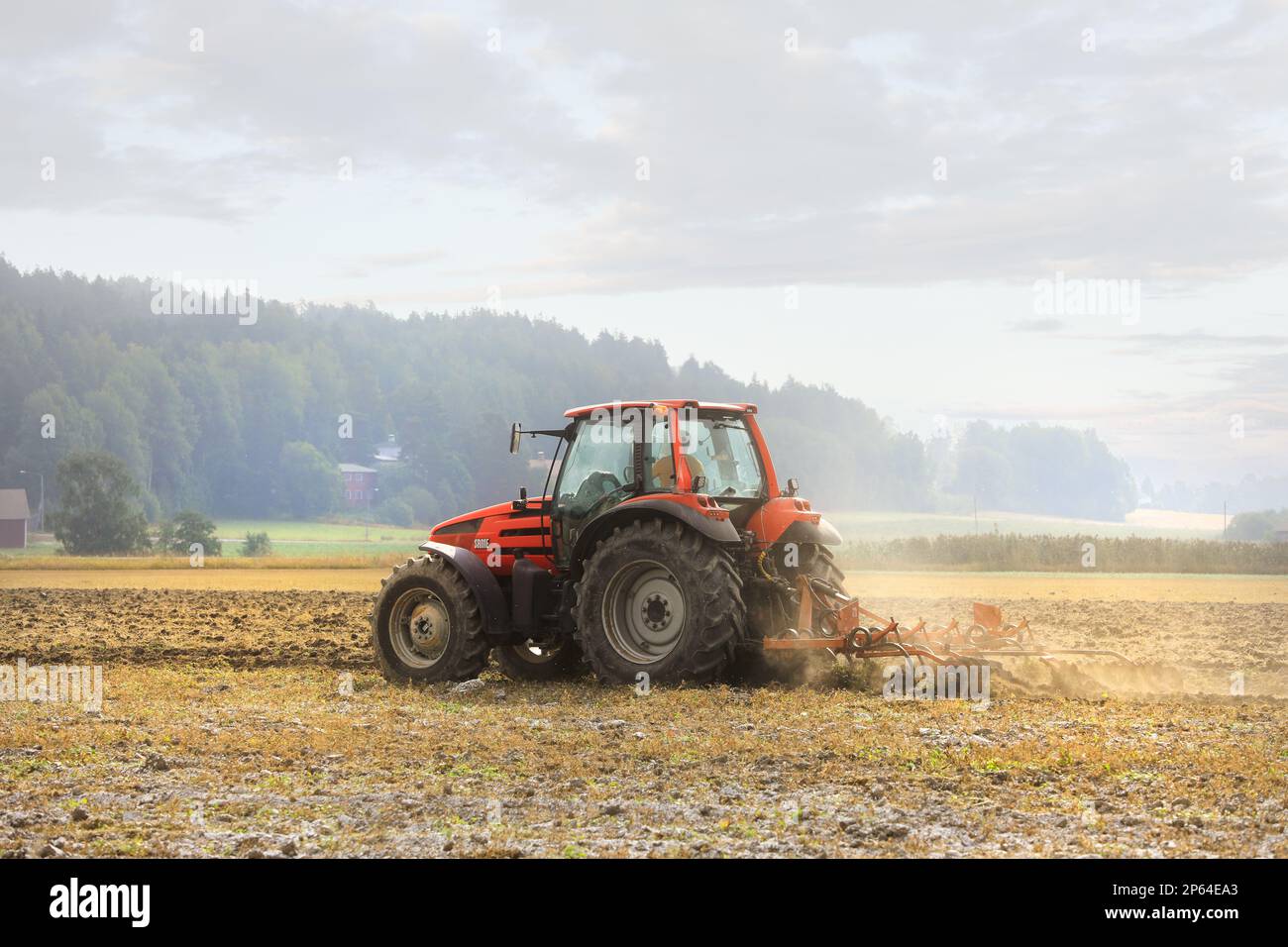 Plowing the field with Same farm tractor and plough on a misty day of ...