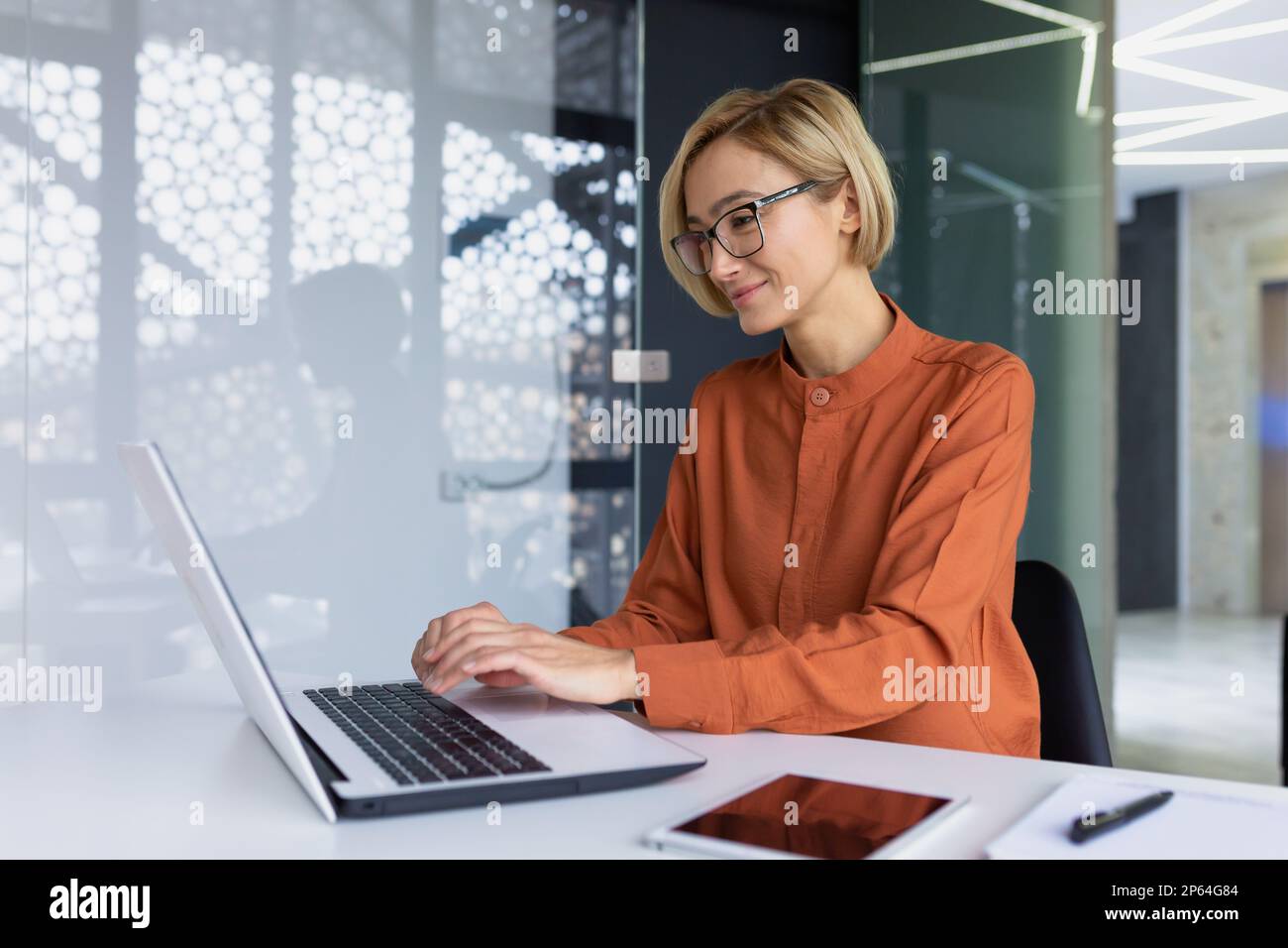 Beautiful young businesswoman inside office working with laptop, blonde ...