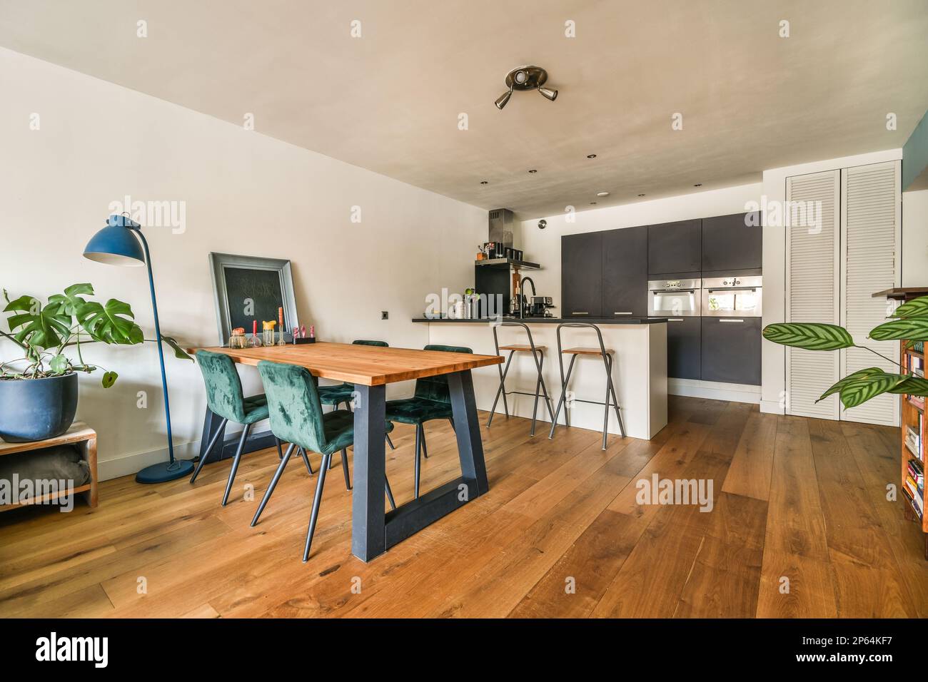 a living room with wood flooring and an open kitchen area in the back wall to the room is white ...