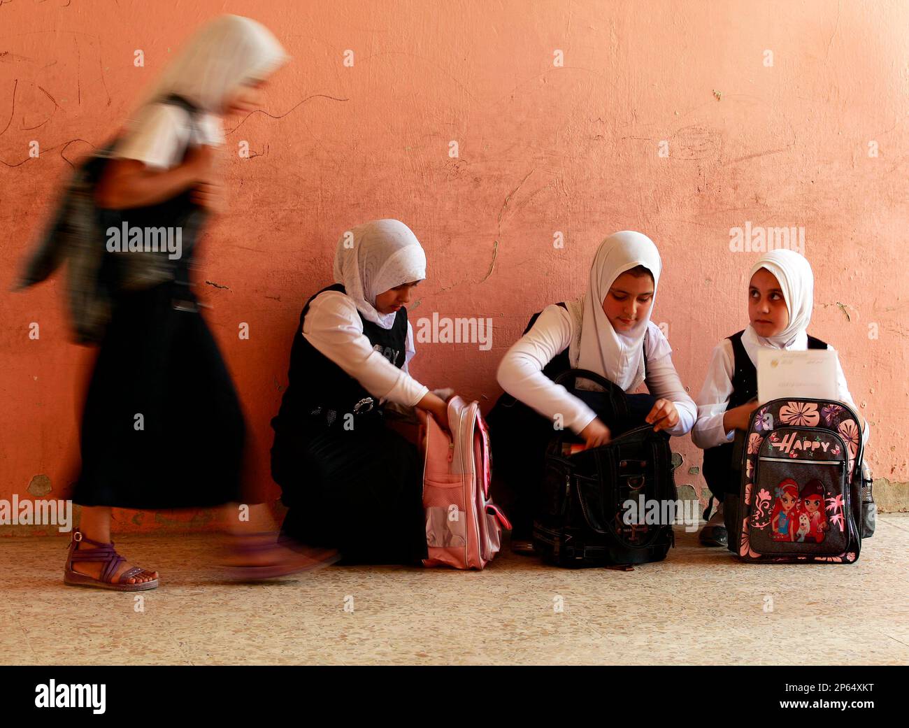 Iraqi school children walk together out of their classroom, in the Sadr ...