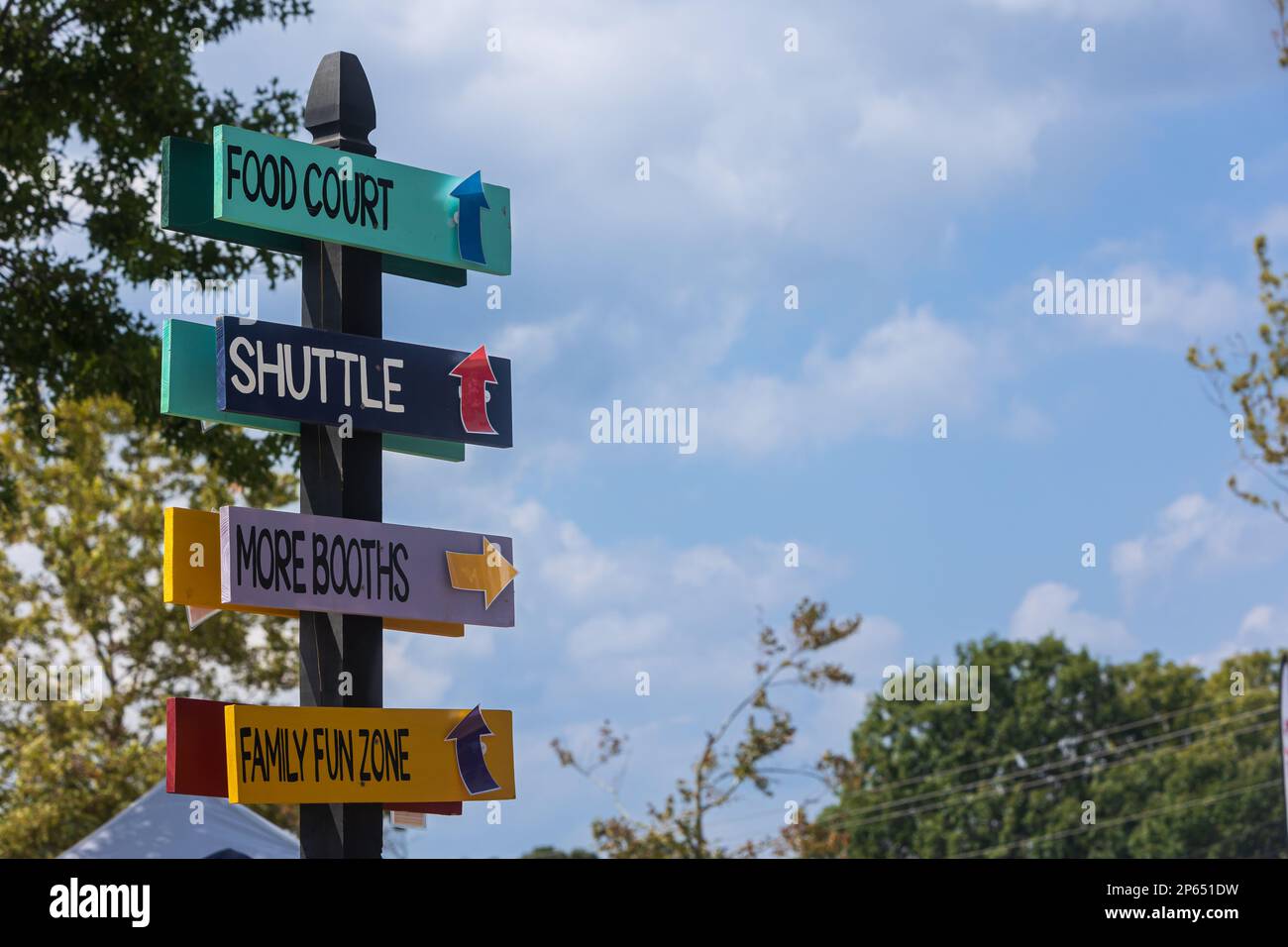 Painted wooden signs on a pole give info and directions with arrows at ...