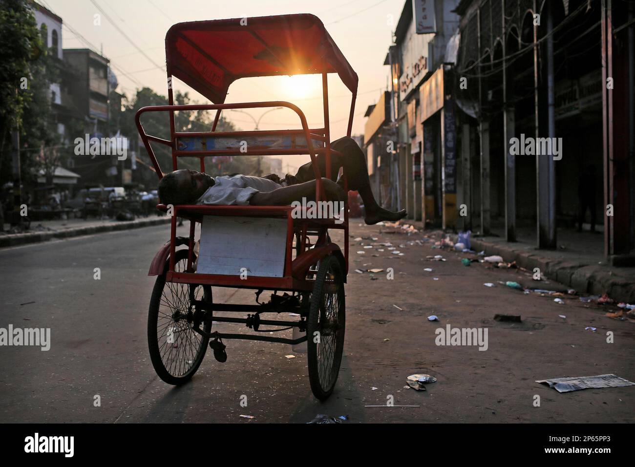 An Indian rickshaw puller sleeps on his bicycle in the street in New ...