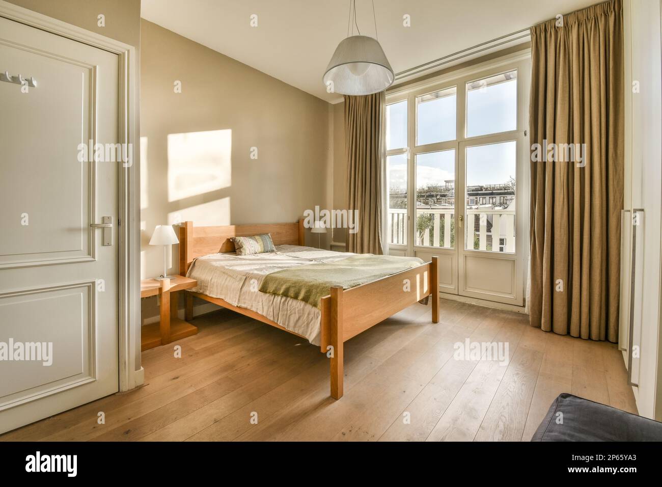 a bedroom with wood flooring and large windows looking out onto the ...