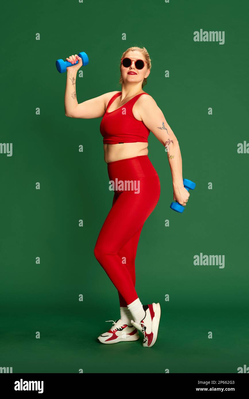 Training with gym equipment. Full-length portrait of woman in red ...