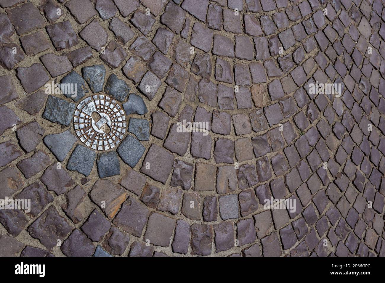 Old metal sewer hatch in the middle of the road, laid out of a smooth ...