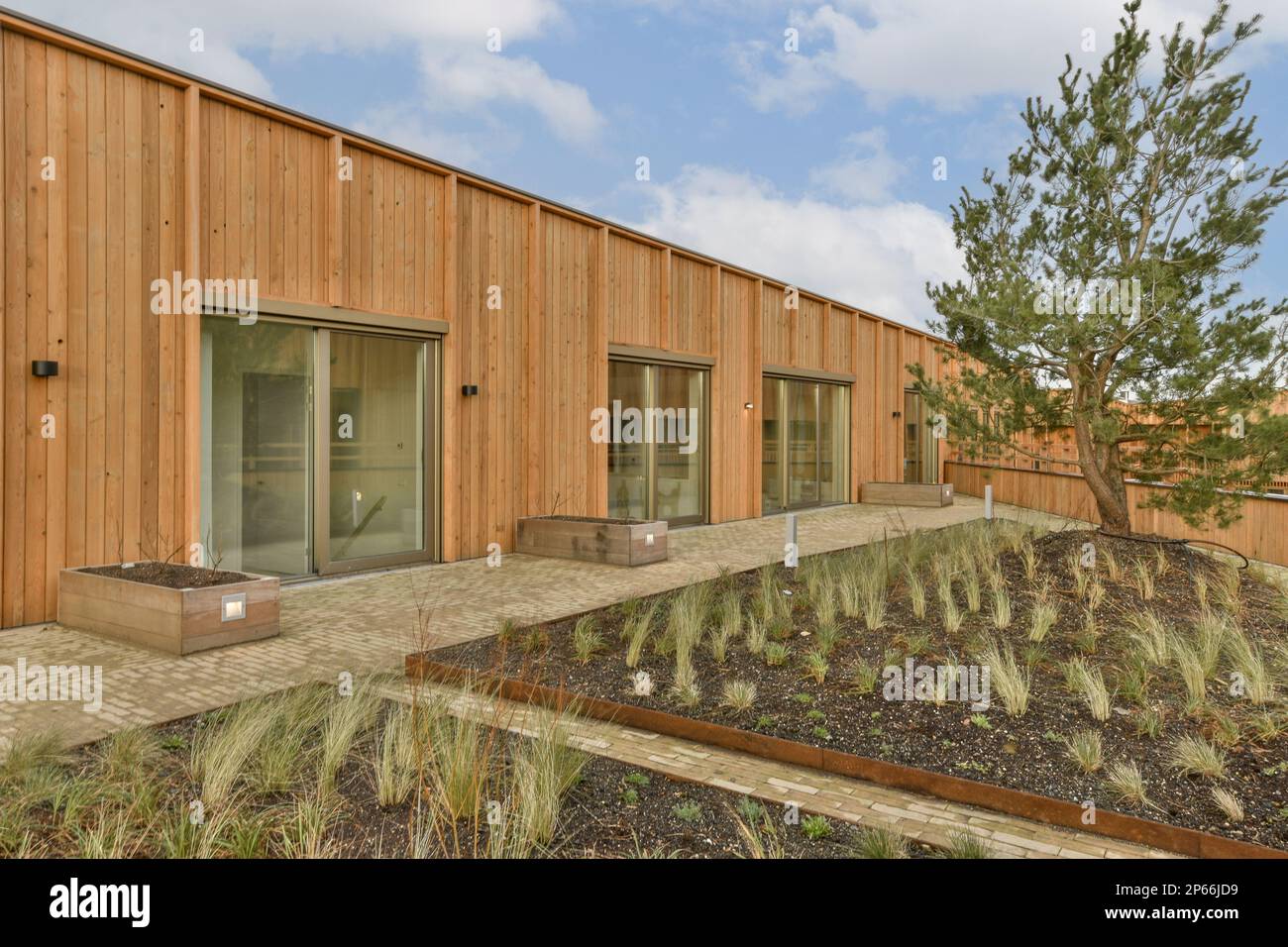 a building with wood sidings on the side and green plants in the ...