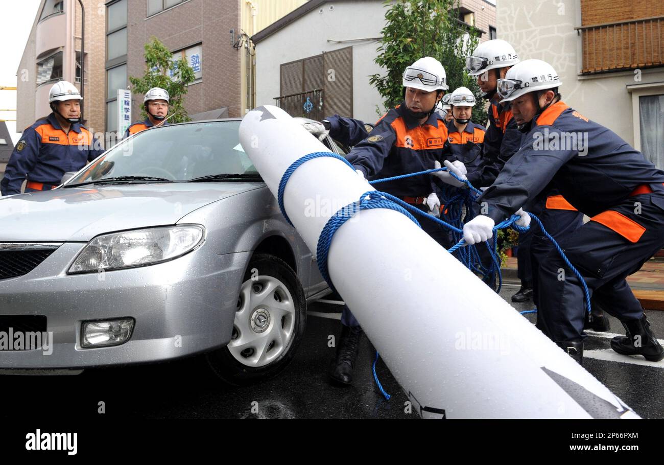 Firefighters remove a mock collapsed utility pole on a car during a ...