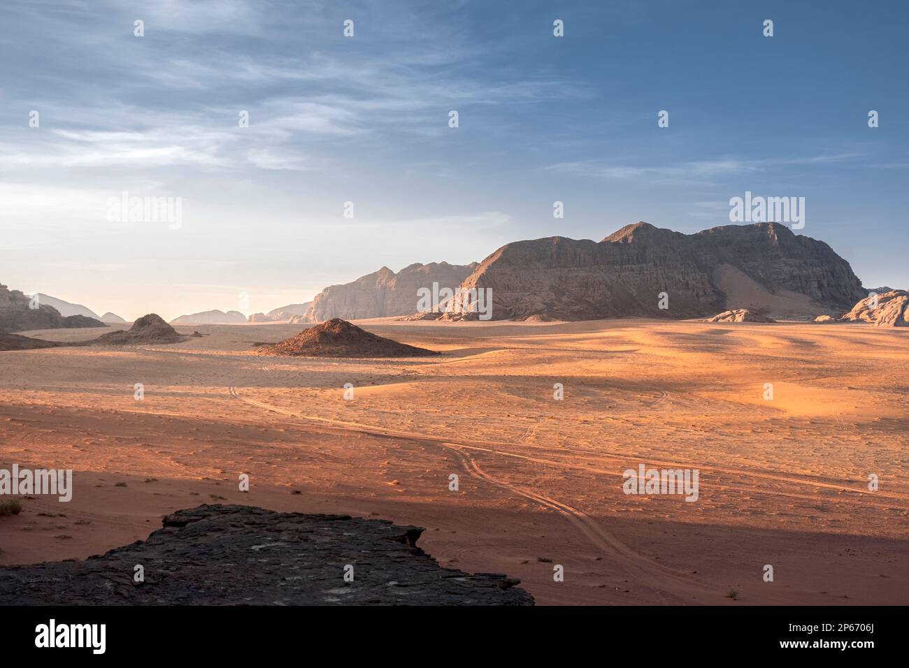 Wadi Rum plain at sunrise with soft light over the sand dunes and ...