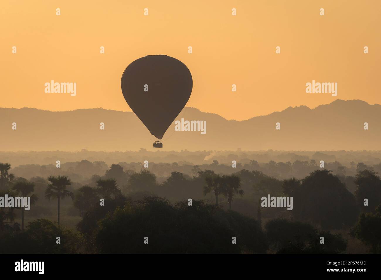 Hot-air balloon at sunrise against mountains, Bagan (Pagan), Myanmar ...