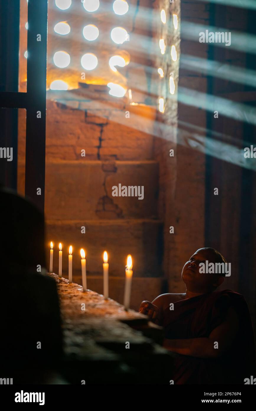 Novice monk inside temple looking up to Buddhist statue, Bagan (Pagan ...