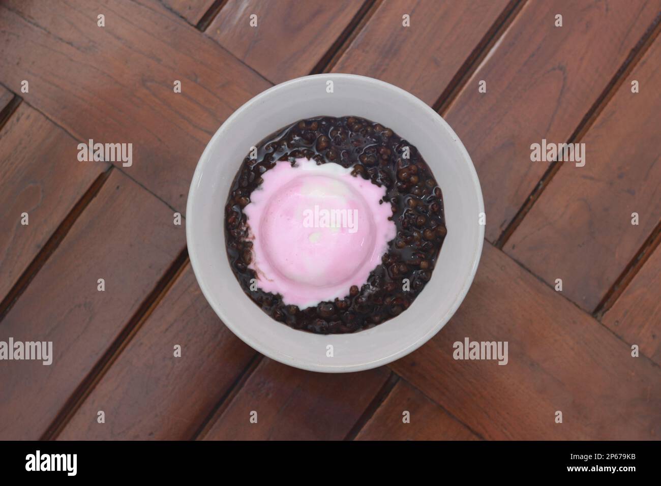 close up of a bowl of black sticky rice porridge topped with strawberry ...