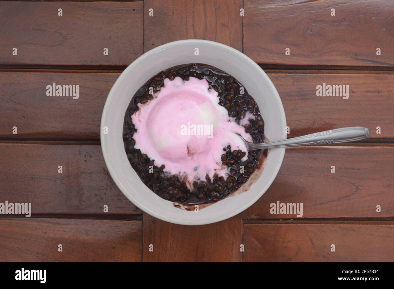 close up of a bowl of black sticky rice porridge topped with strawberry ...