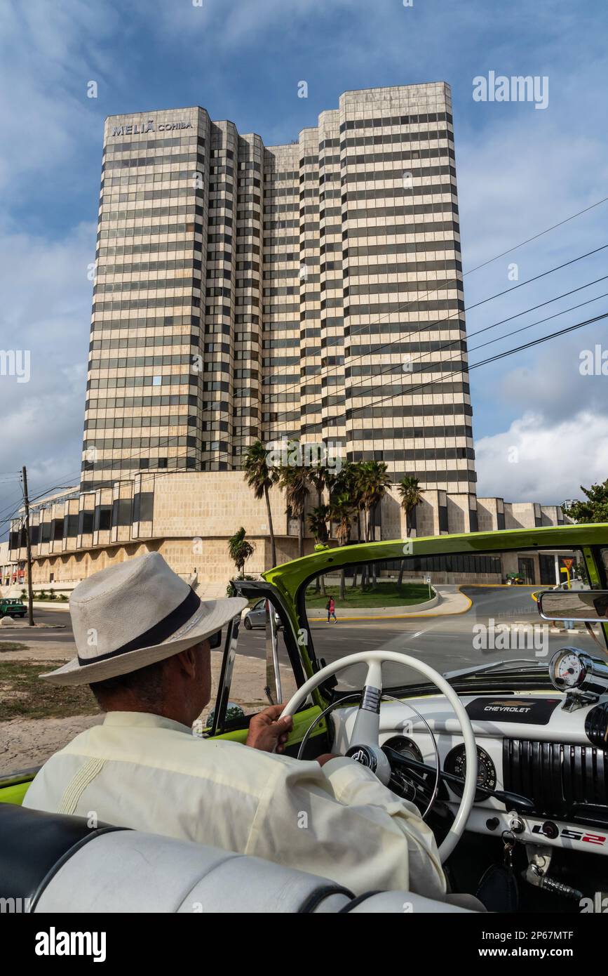 Driver with panama hat in green open top Chevrolet classic car driving ...