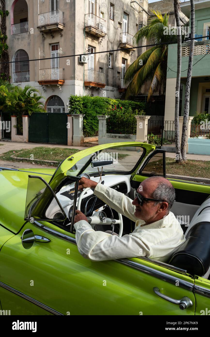 Driver in green open top Chevrolet classic car parked in suburb, Havana ...
