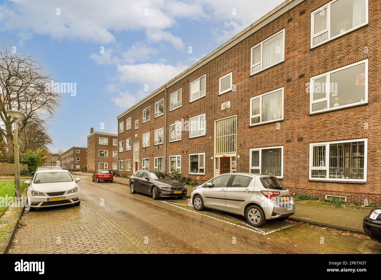 some cars parked on the side of a street in front of a brick building ...