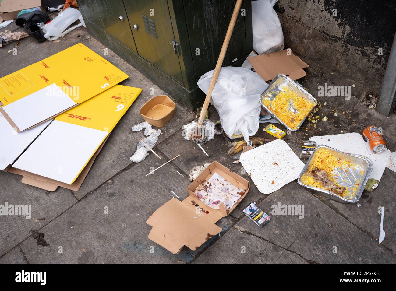 Packaging litter and food waste is spread across the pavement in a ...