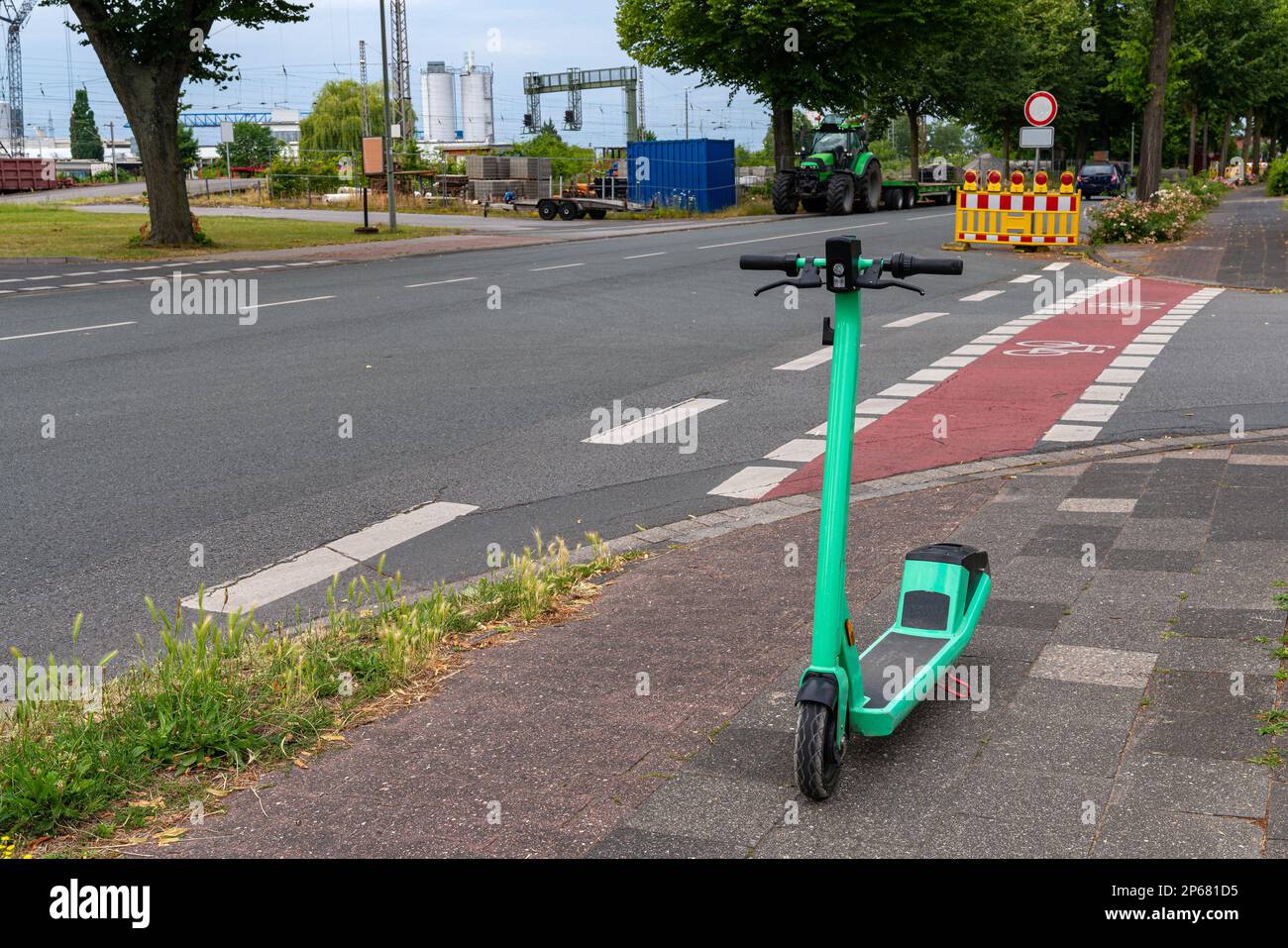 Green electric scooter left on the sidewalk. Barrier and stop sign in ...