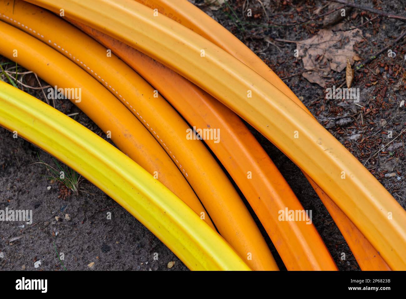 Bundle of yellow-orange electrical cables lying on the ground. Close up ...