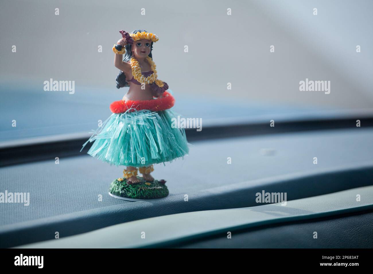 A hula dancer figurine sits in the back window of a car on display ...