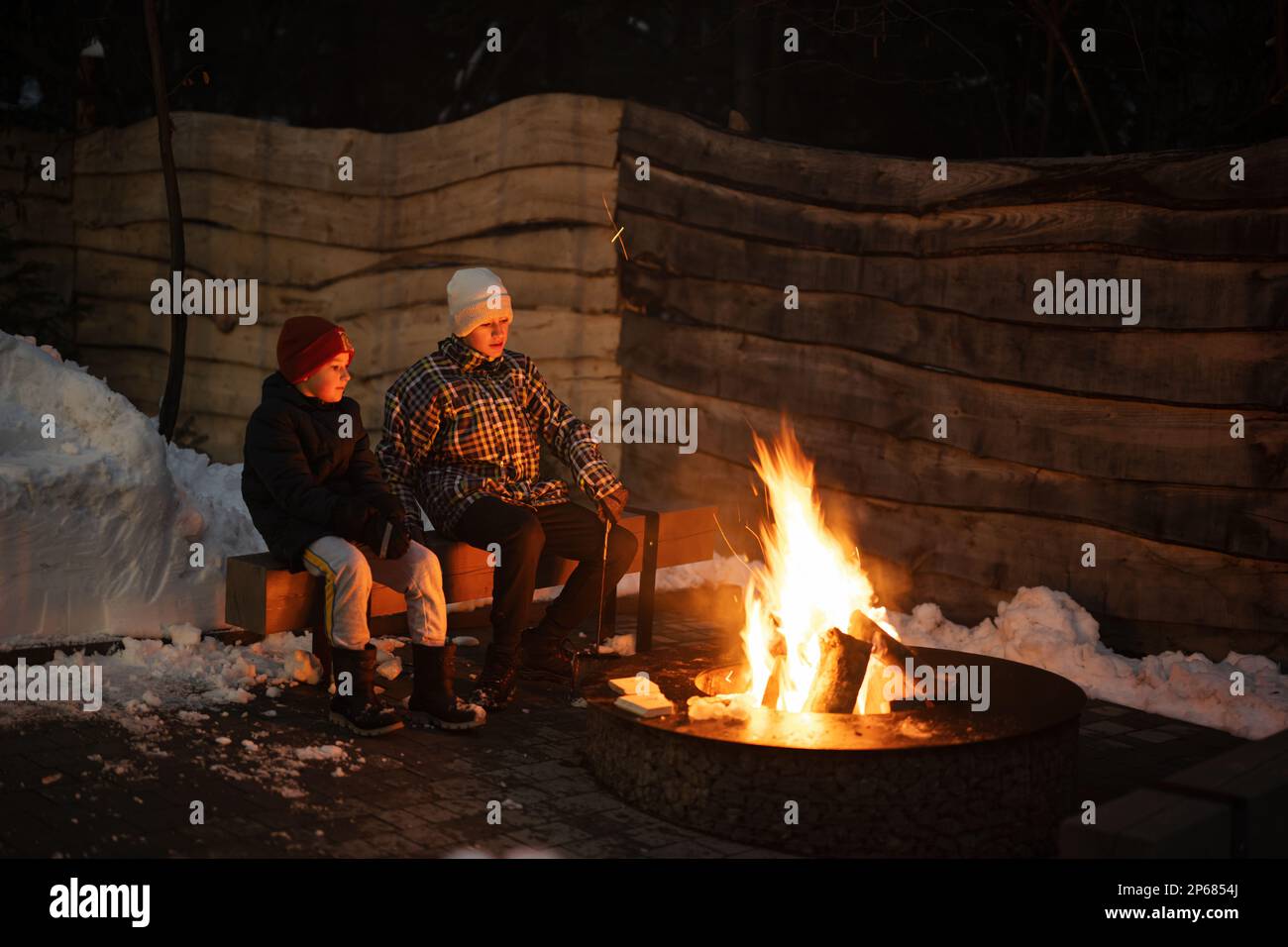 Two brothers sit by the fire pit in winter night Stock Photo - Alamy
