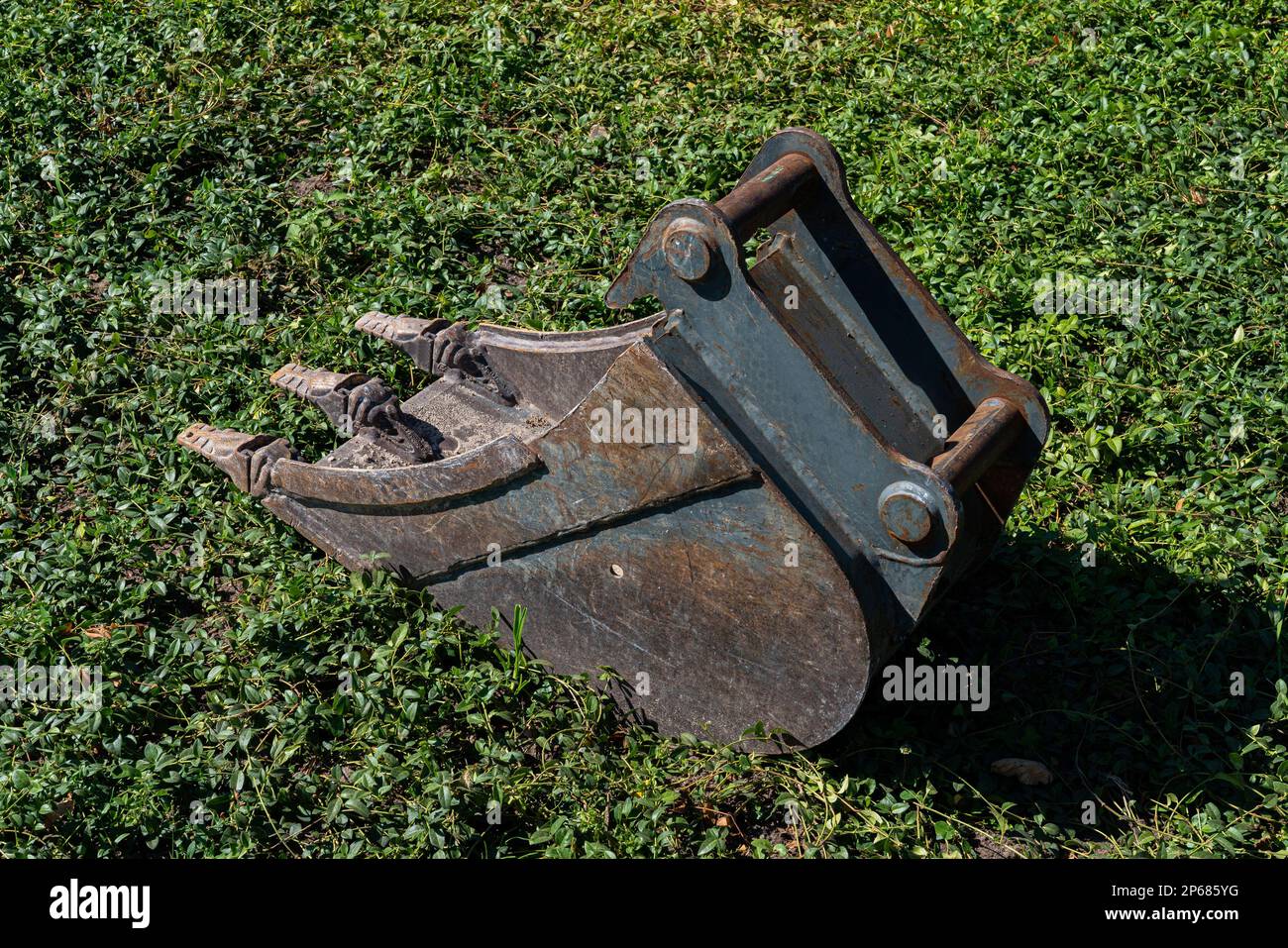 Excavator bucket lying on green grass. Close up Stock Photo - Alamy