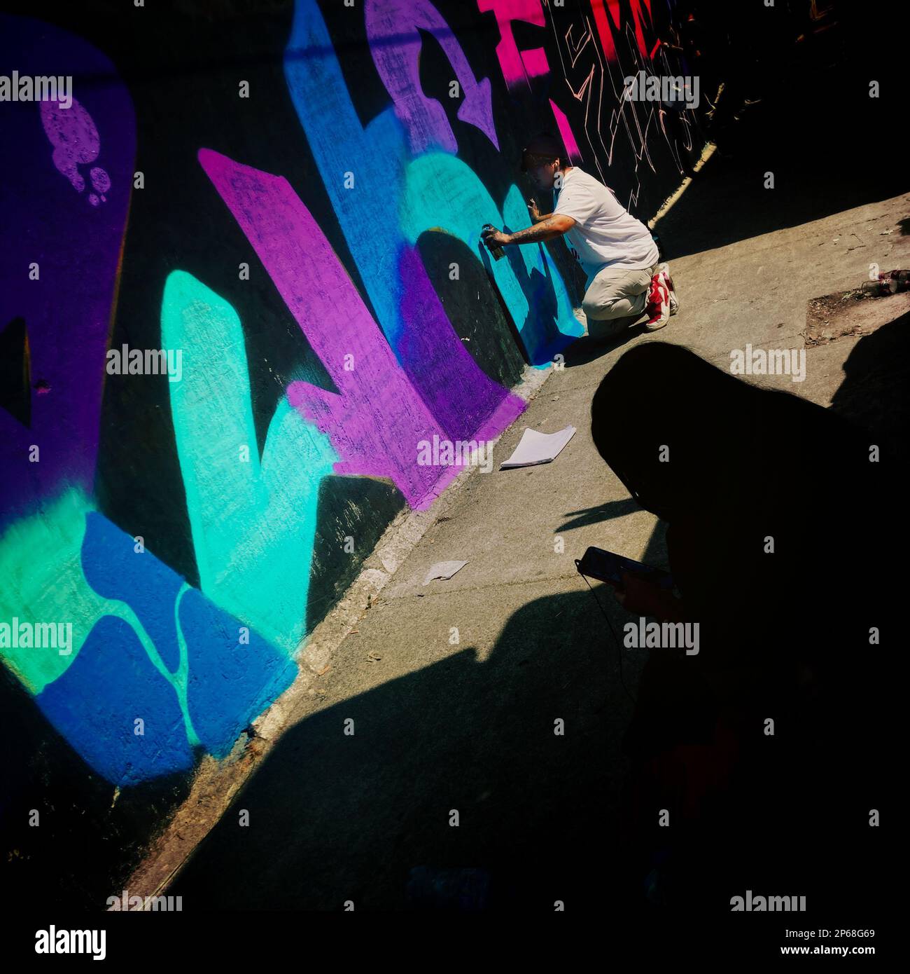 A Mexican street artist paints graffiti on the wall of a cemetery ...